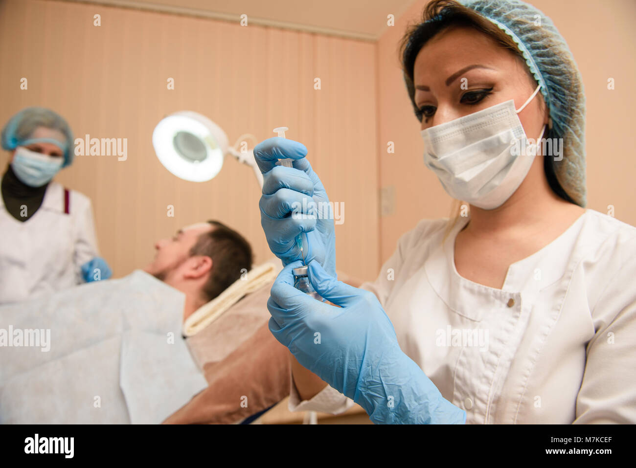 Close-up of doctor hands in rubber gloves with syringe. Doctor takes ...