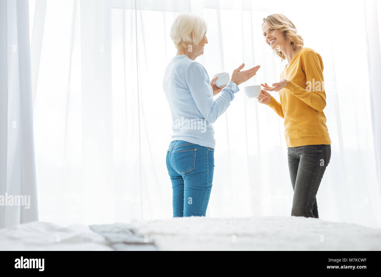 Cheerful women of different age having an emotional talk and smiling ...