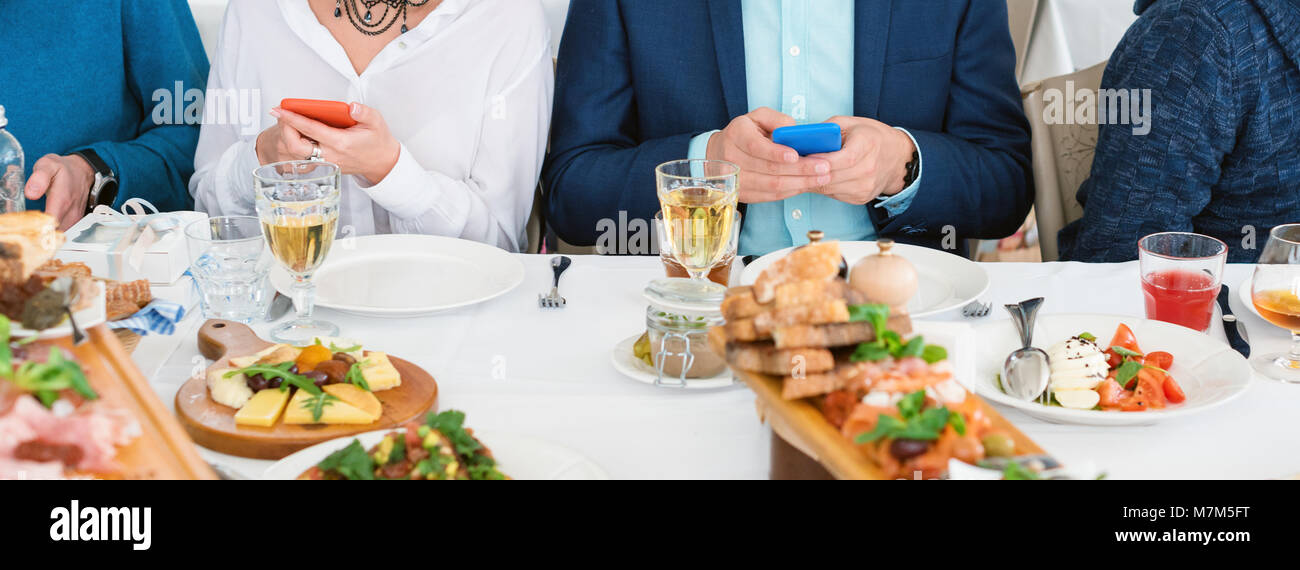 Friends sitting in cafe, eating and drinking alcohol while using mobile ...