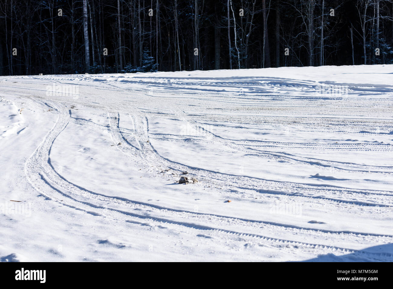 snowy winter road covered in deep snow with car tire tracks going in ...
