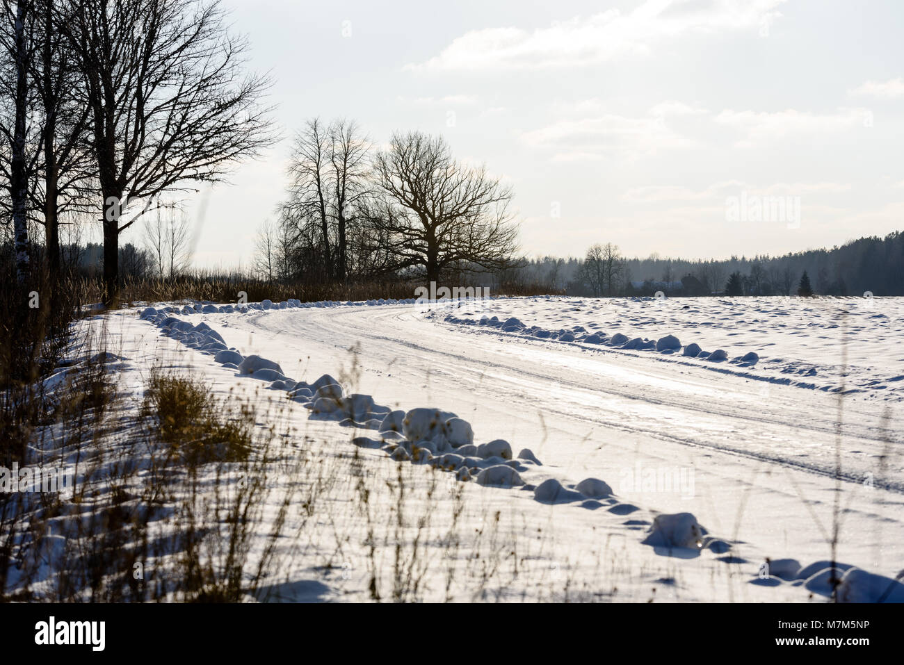snowy winter road covered in deep snow with car tire tracks going in ...