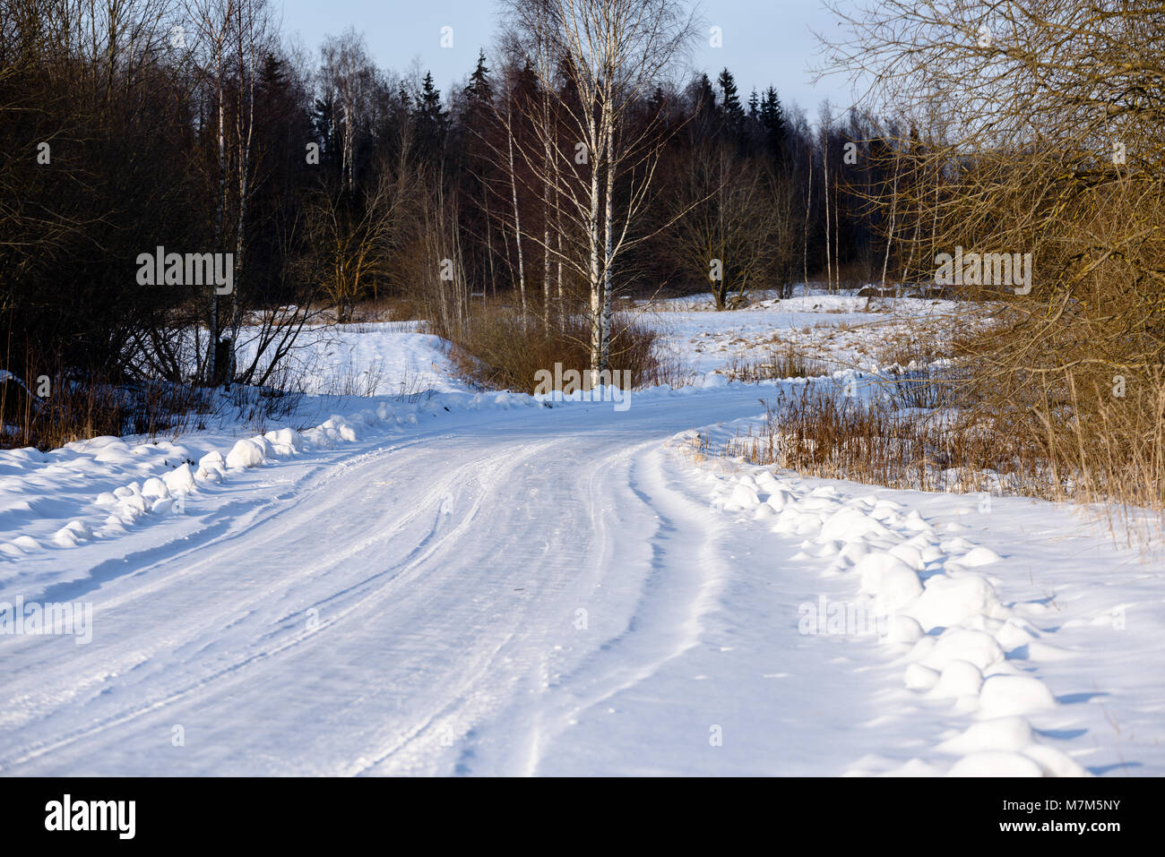 snowy winter road covered in deep snow with car tire tracks going in ...