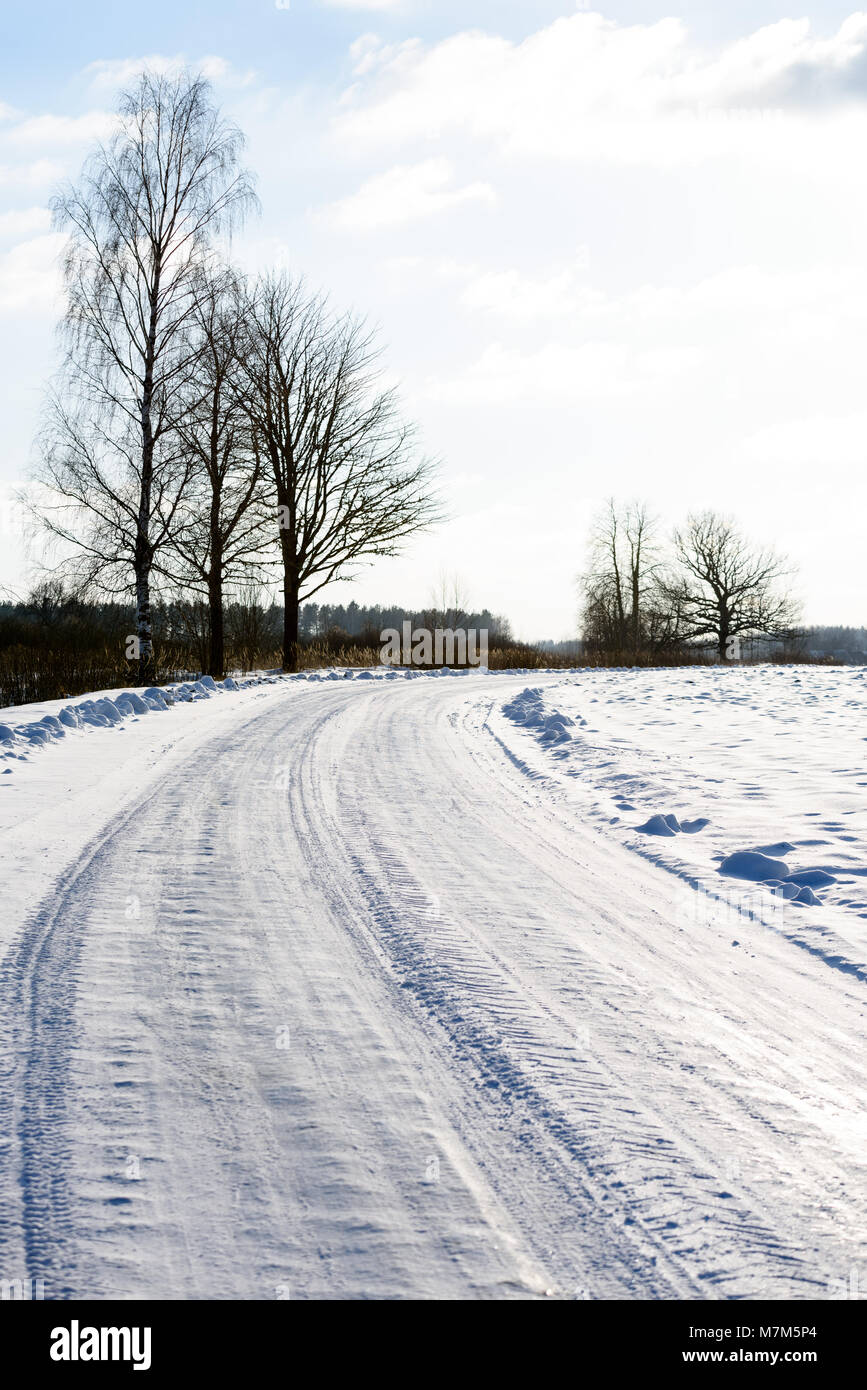 snowy winter road covered in deep snow with car tire tracks going in ...