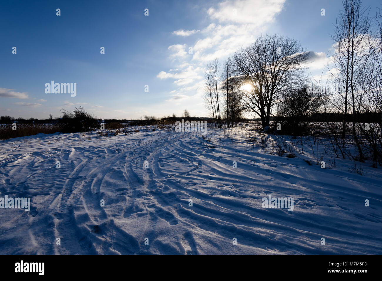 snowy winter road covered in deep snow with car tire tracks going in ...