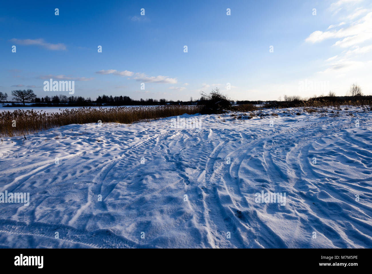 snowy winter road covered in deep snow with car tire tracks going in ...