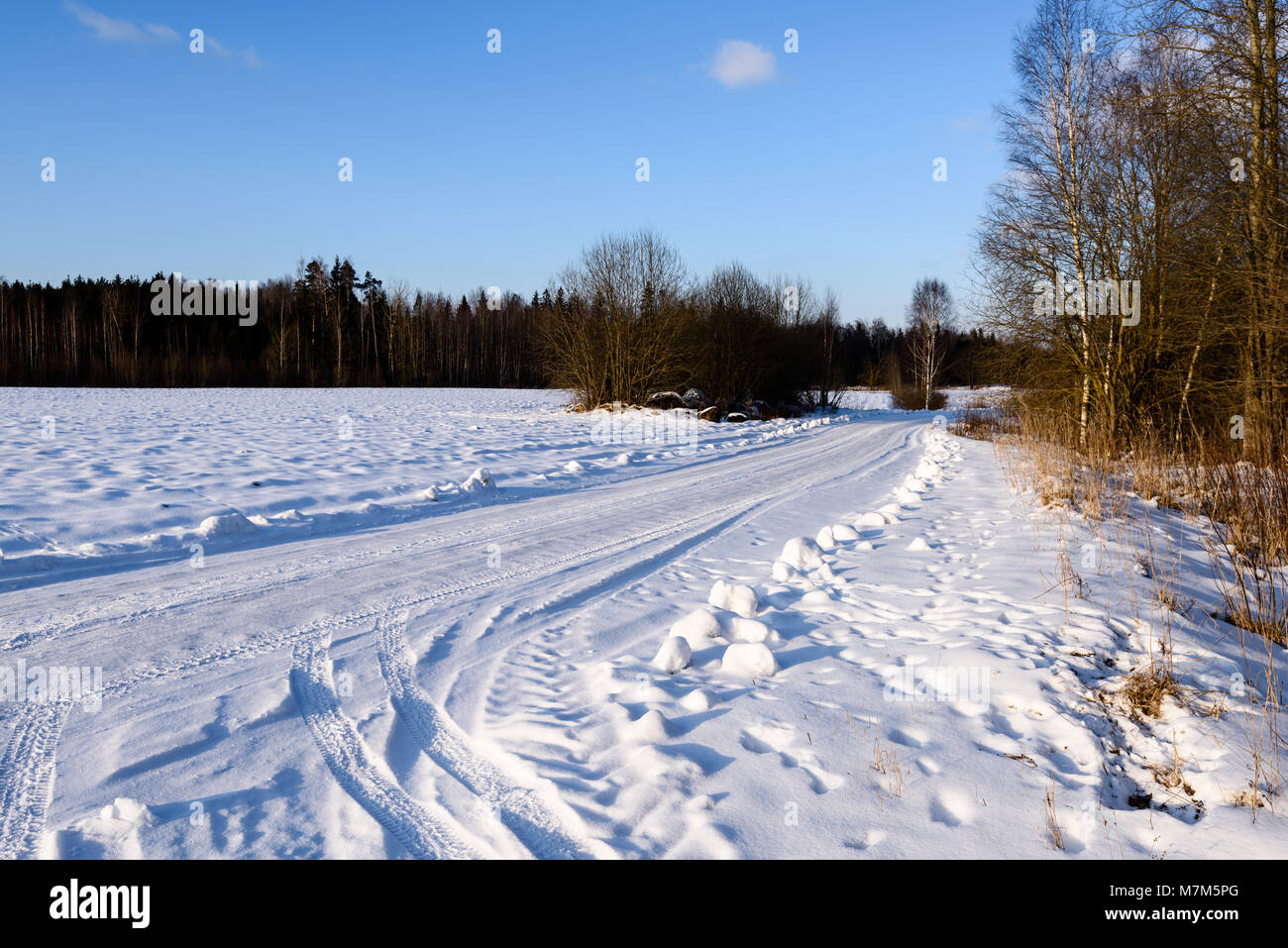 snowy winter road covered in deep snow with car tire tracks going in ...