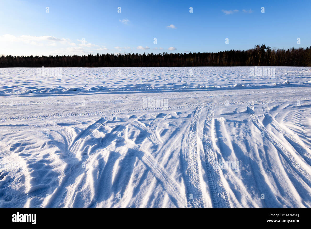 snowy winter road covered in deep snow with car tire tracks going in ...