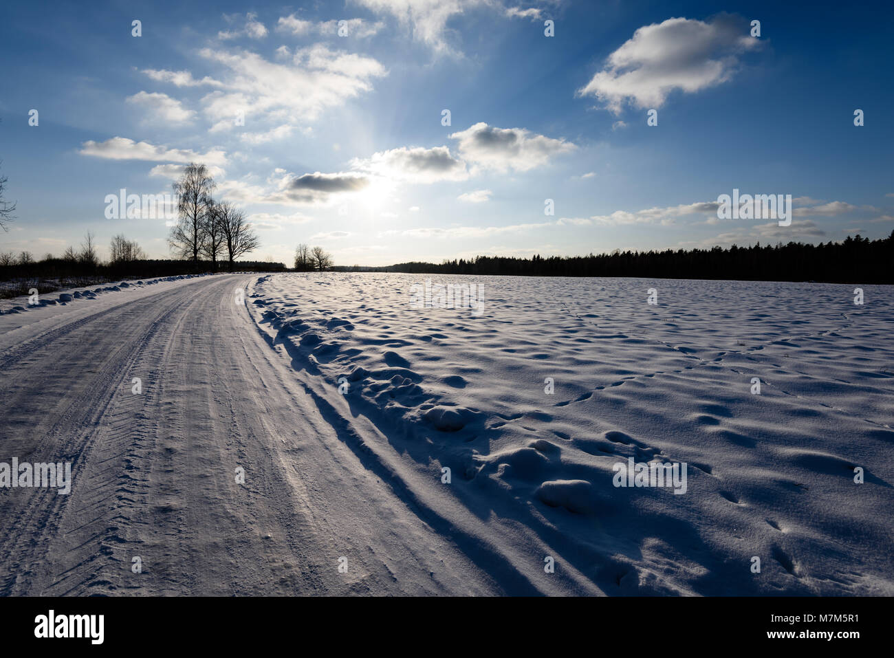 snowy winter road covered in deep snow with car tire tracks going in ...