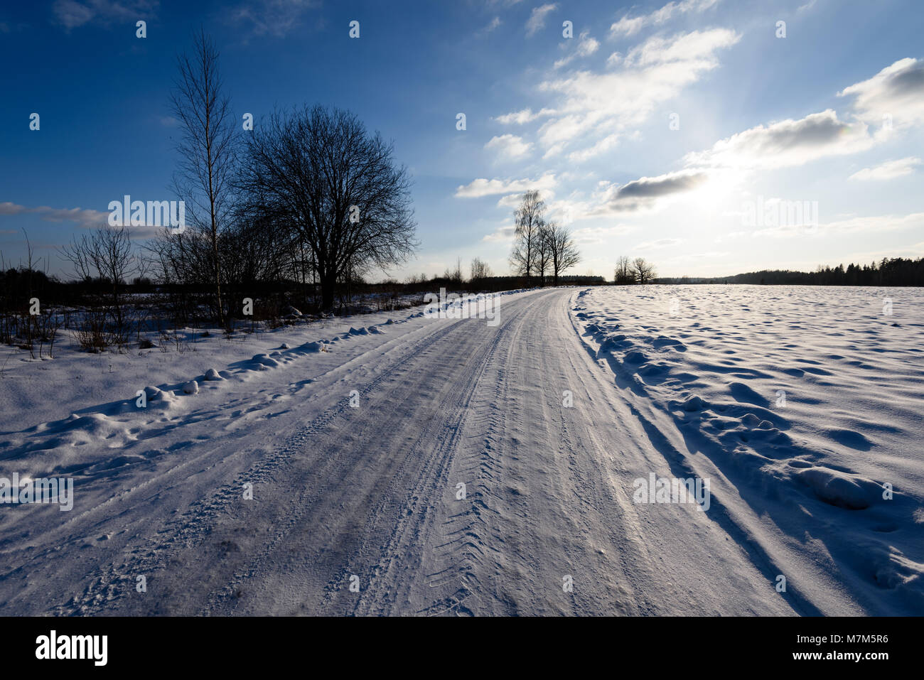 snowy winter road covered in deep snow with car tire tracks going in ...