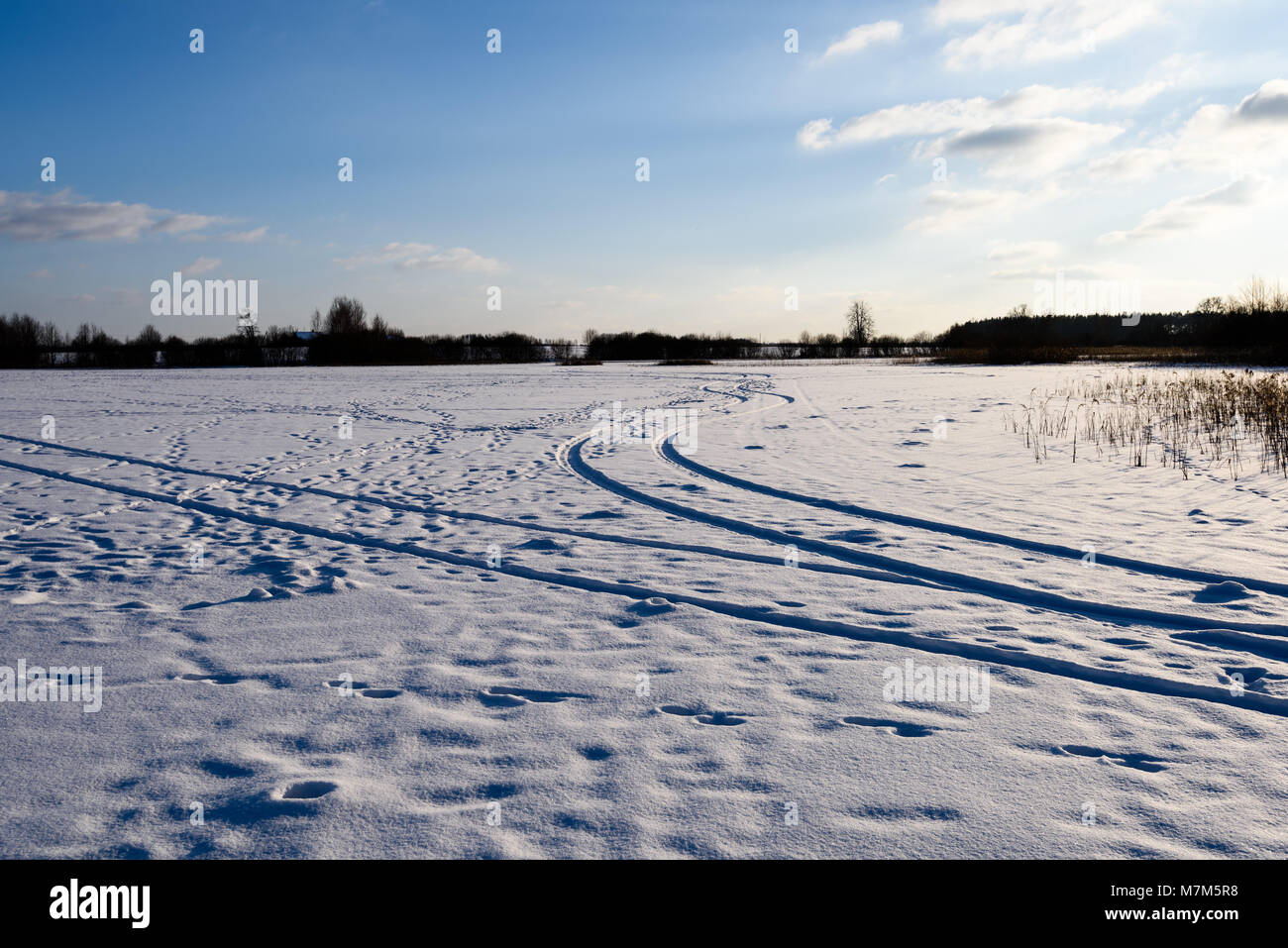 snowy winter road covered in deep snow with car tire tracks going in ...