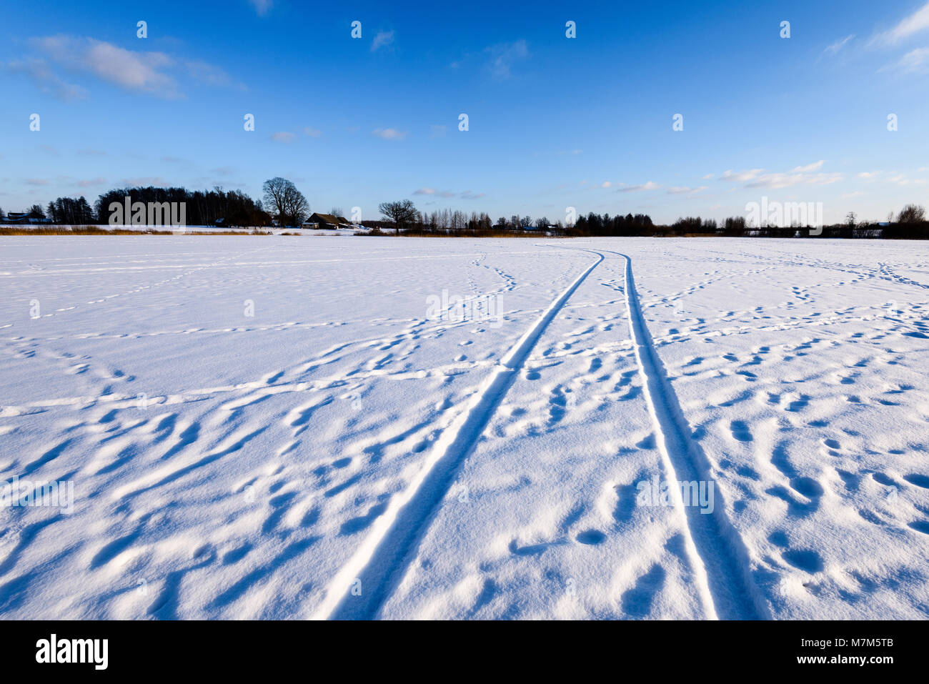 snowy winter road covered in deep snow with car tire tracks going in ...