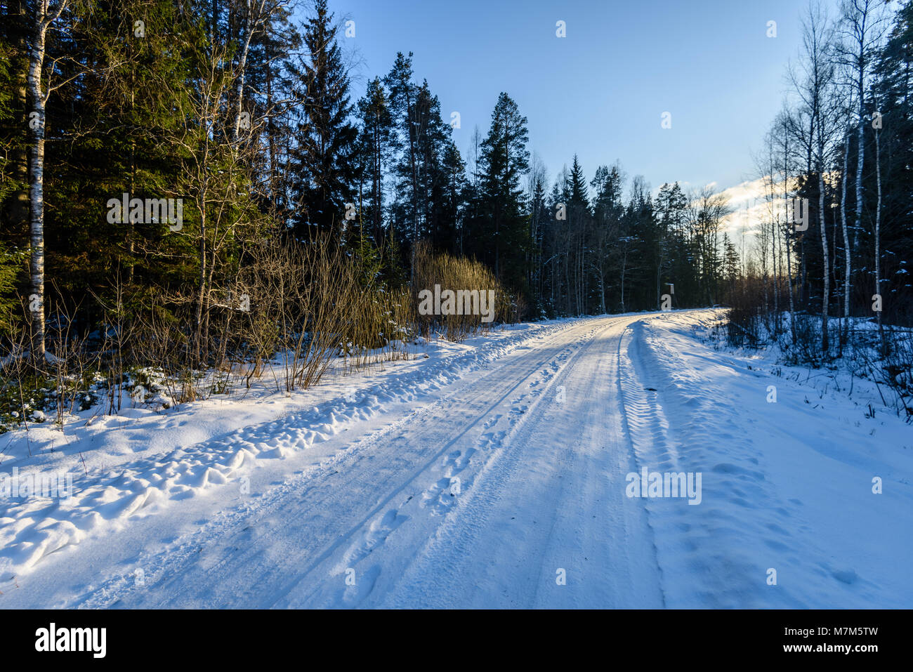 snowy winter road covered in deep snow with car tire tracks going in ...