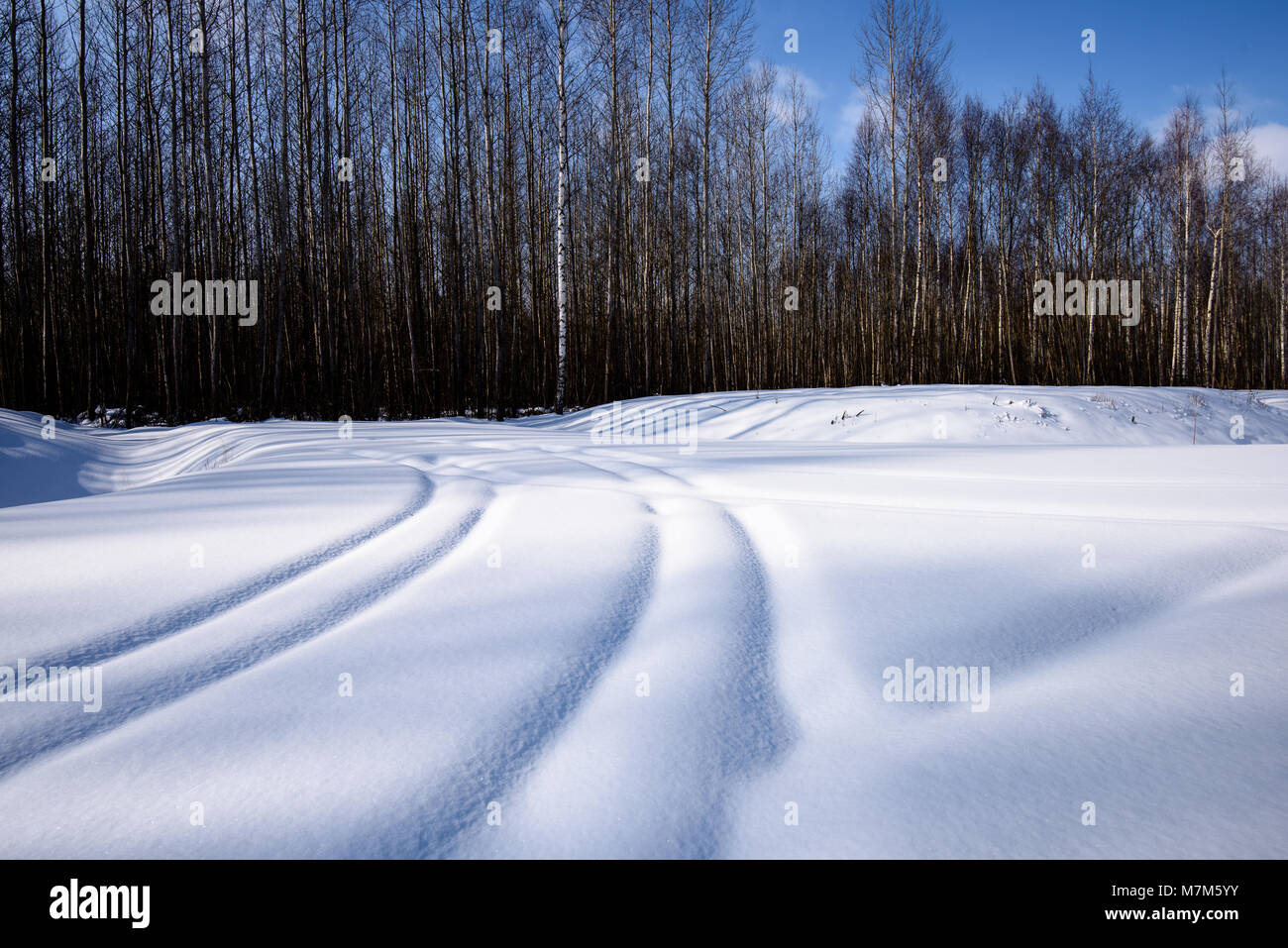 snowy winter road covered in deep snow with car tire tracks going in ...