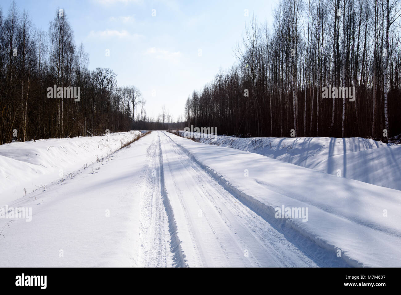 snowy winter road covered in deep snow with car tire tracks going in ...