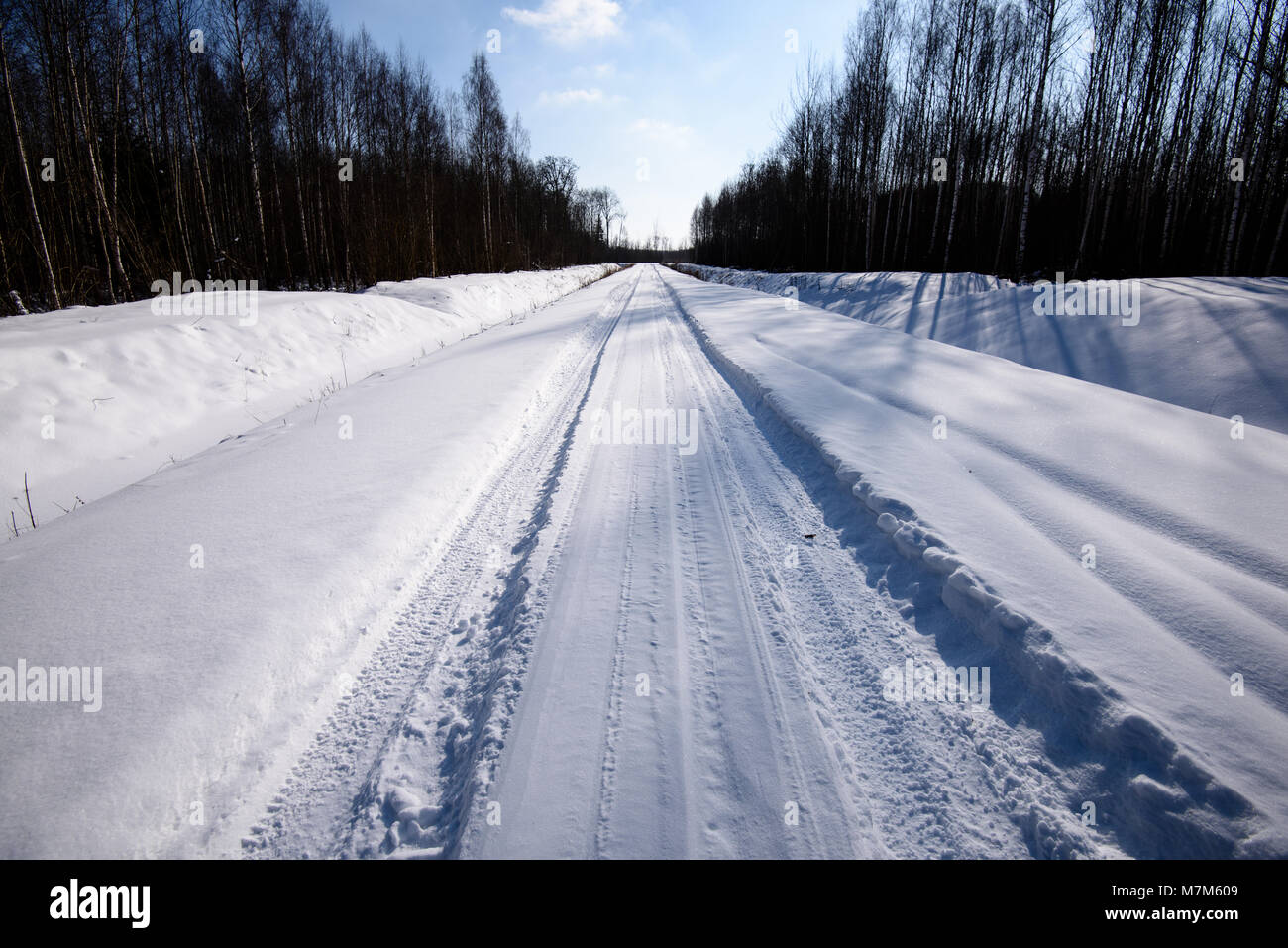 snowy winter road covered in deep snow with car tire tracks going in ...
