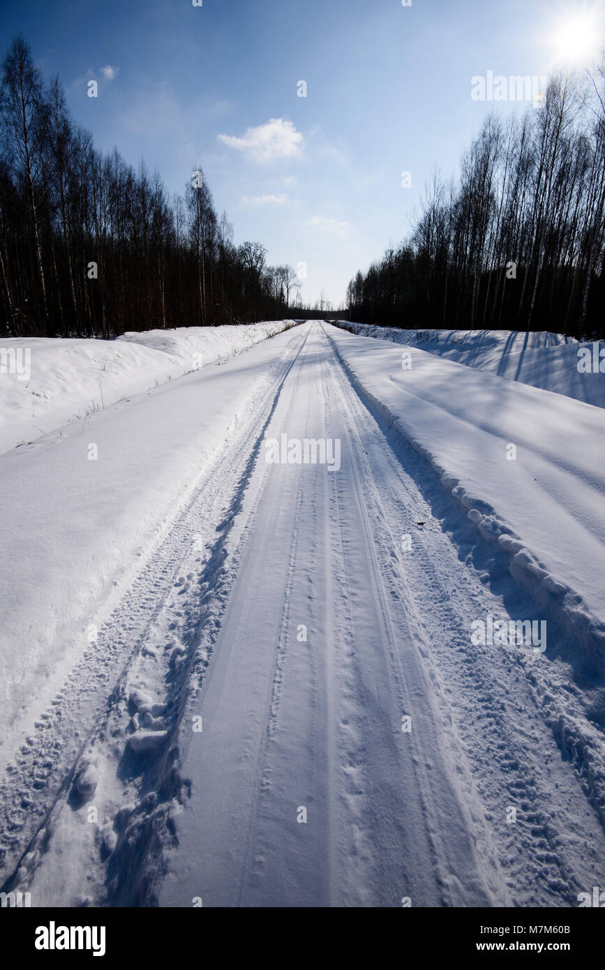 snowy winter road covered in deep snow with car tire tracks going in ...