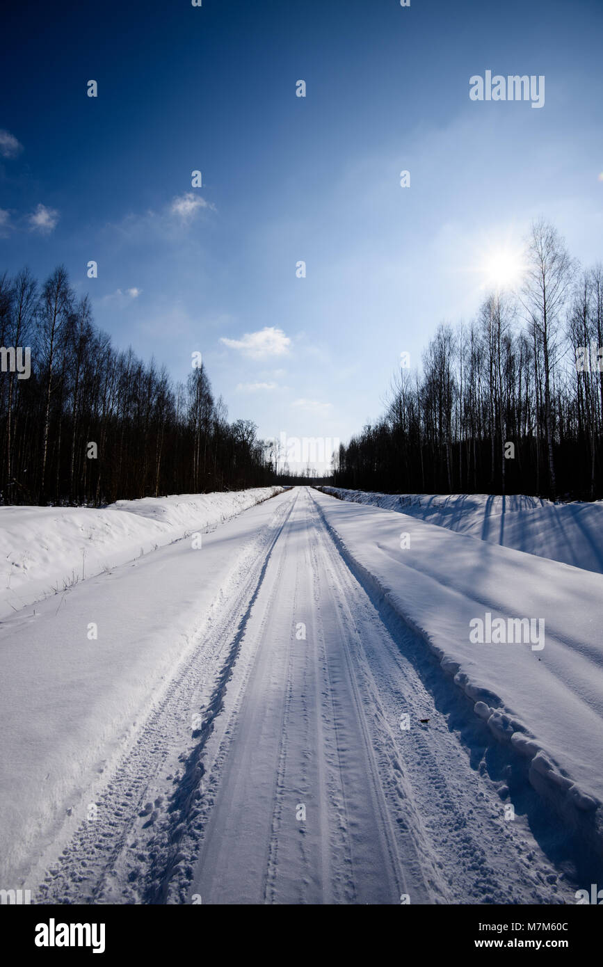 snowy winter road covered in deep snow with car tire tracks going in ...