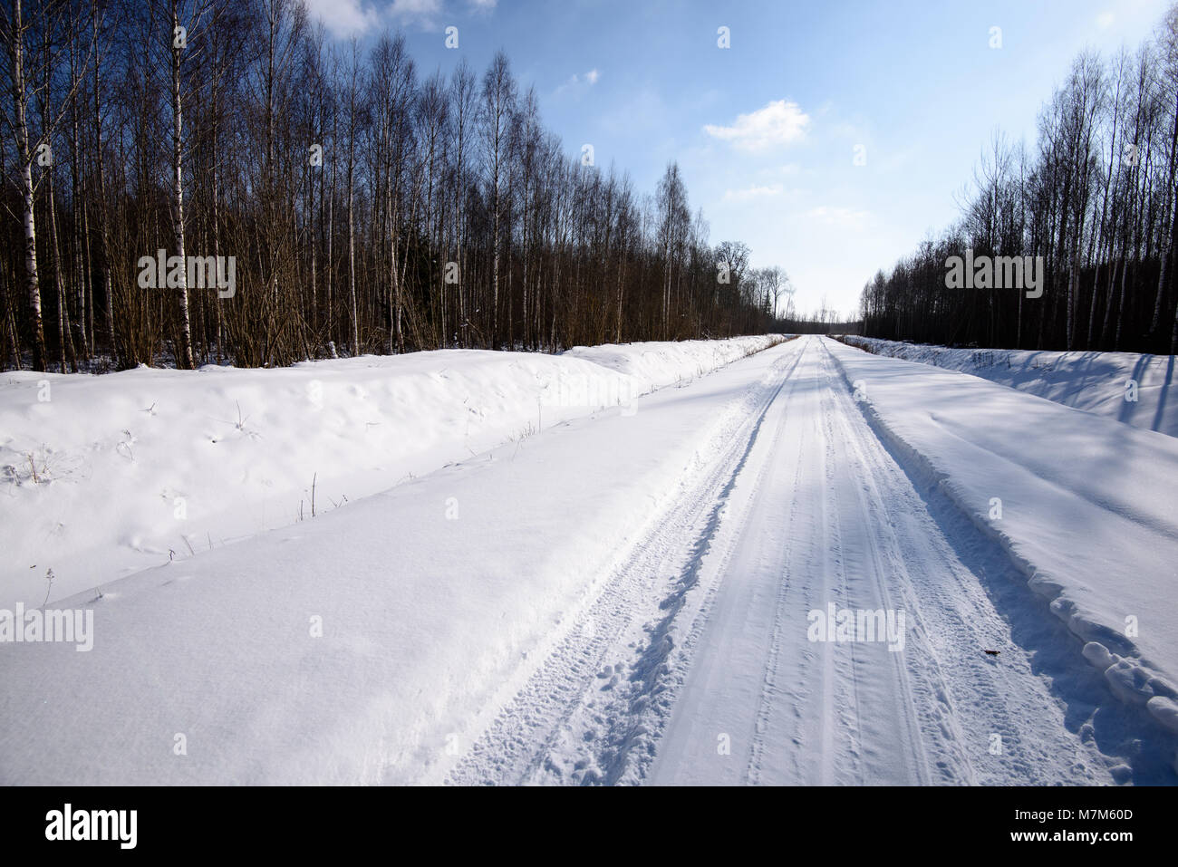 snowy winter road covered in deep snow with car tire tracks going in ...