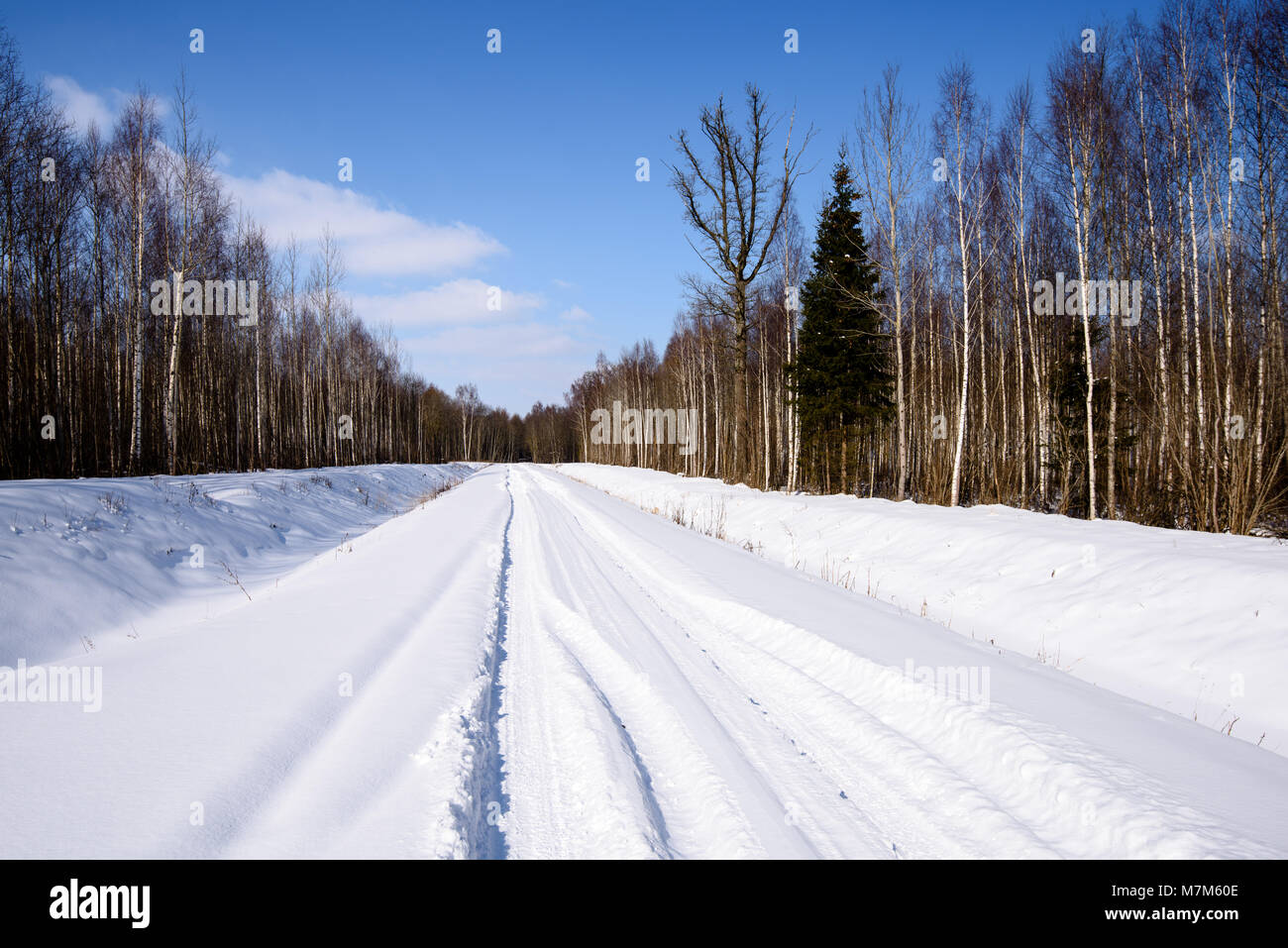 snowy winter road covered in deep snow with car tire tracks going in ...