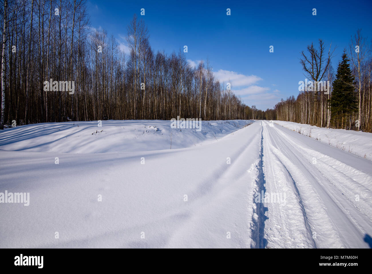 snowy winter road covered in deep snow with car tire tracks going in ...