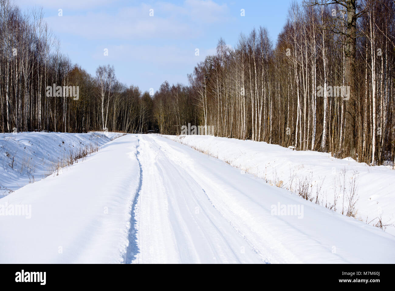 snowy winter road covered in deep snow with car tire tracks going in ...