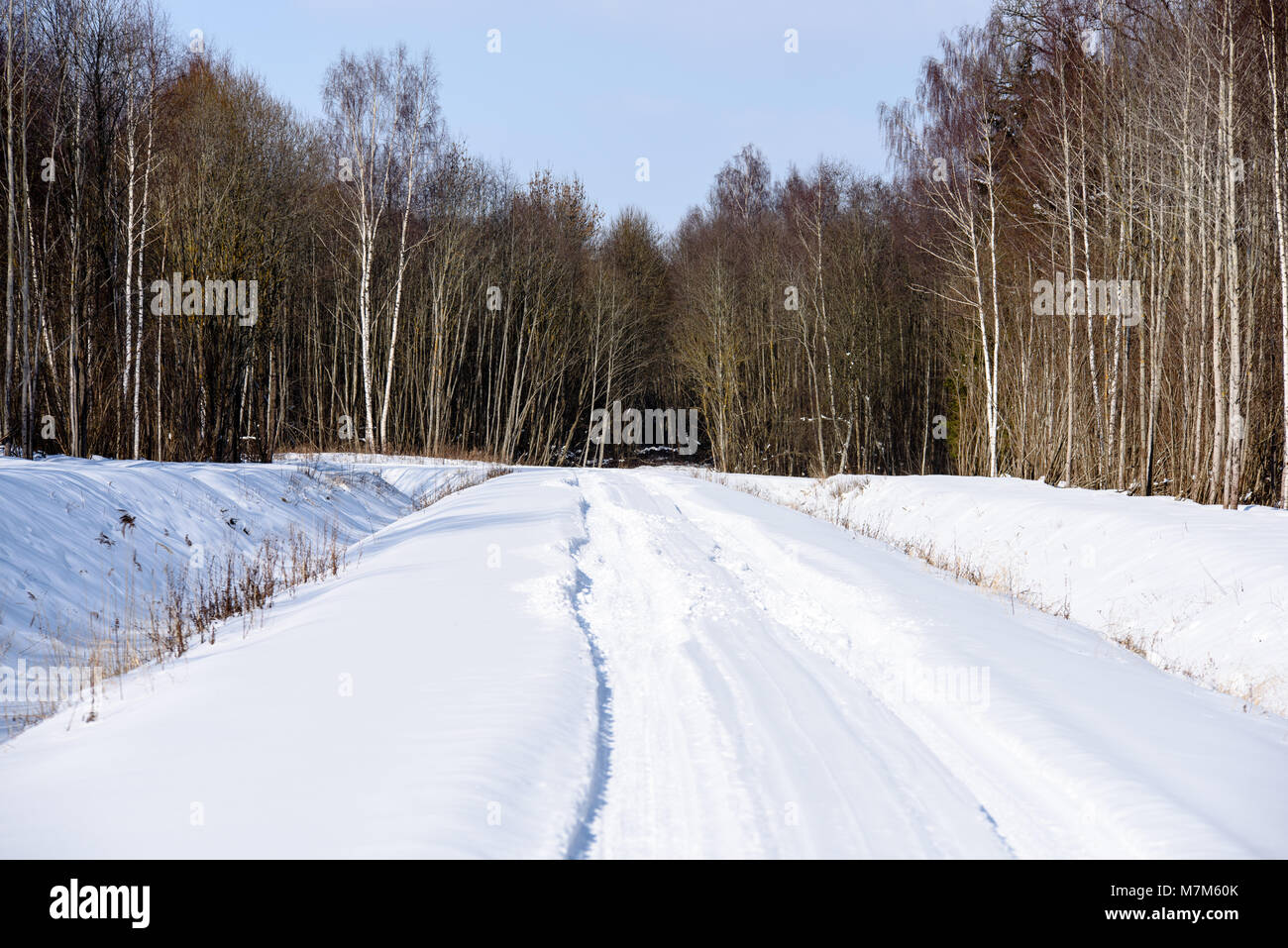 snowy winter road covered in deep snow with car tire tracks going in ...
