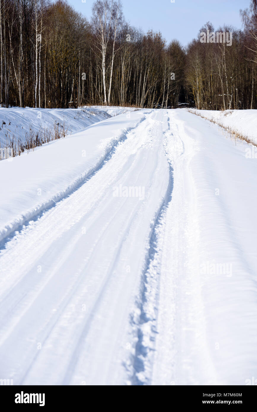 snowy winter road covered in deep snow with car tire tracks going in ...