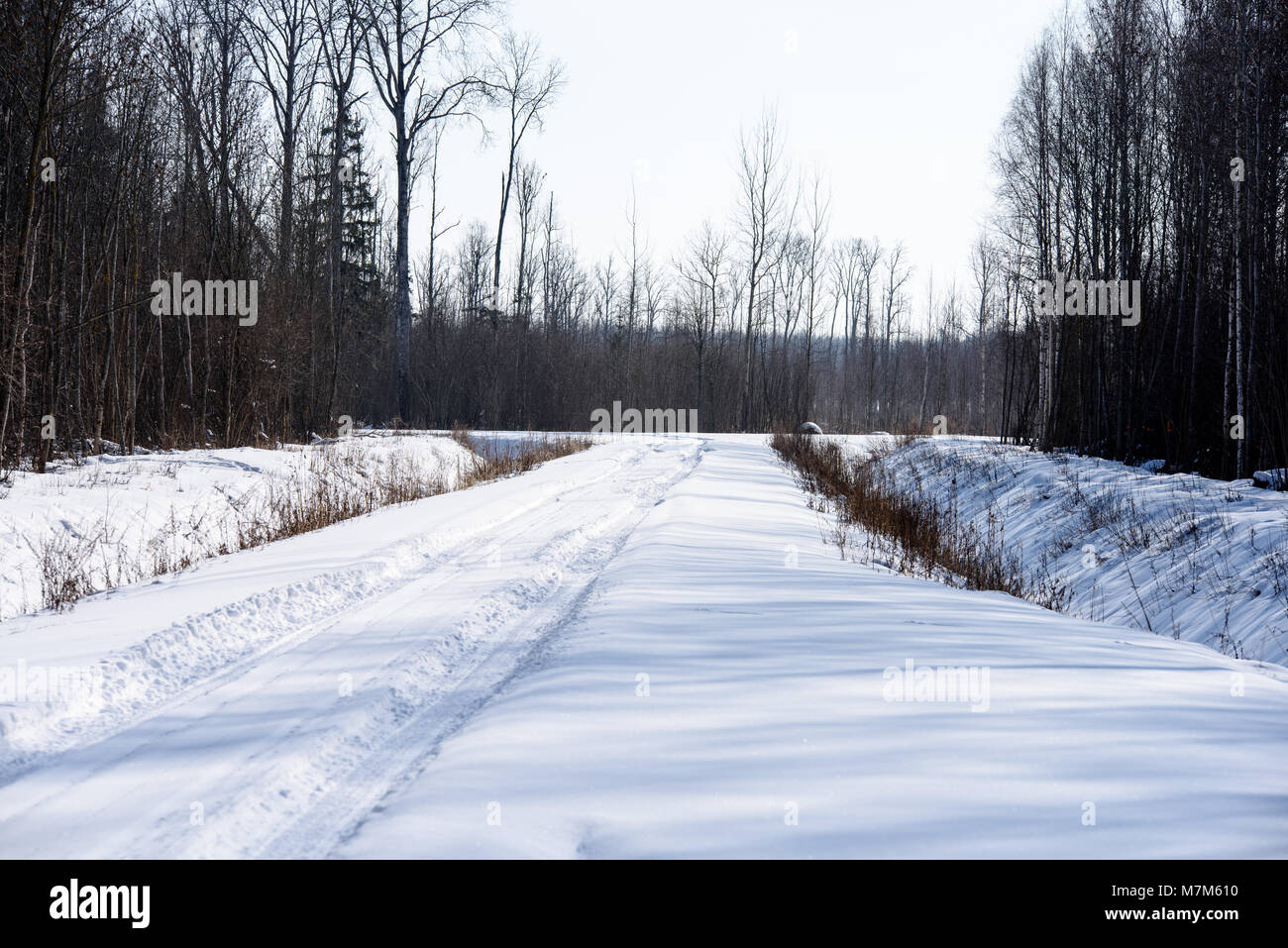 snowy winter road covered in deep snow with car tire tracks going in ...