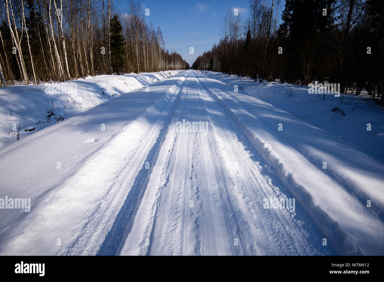 snowy winter road covered in deep snow with car tire tracks going in ...