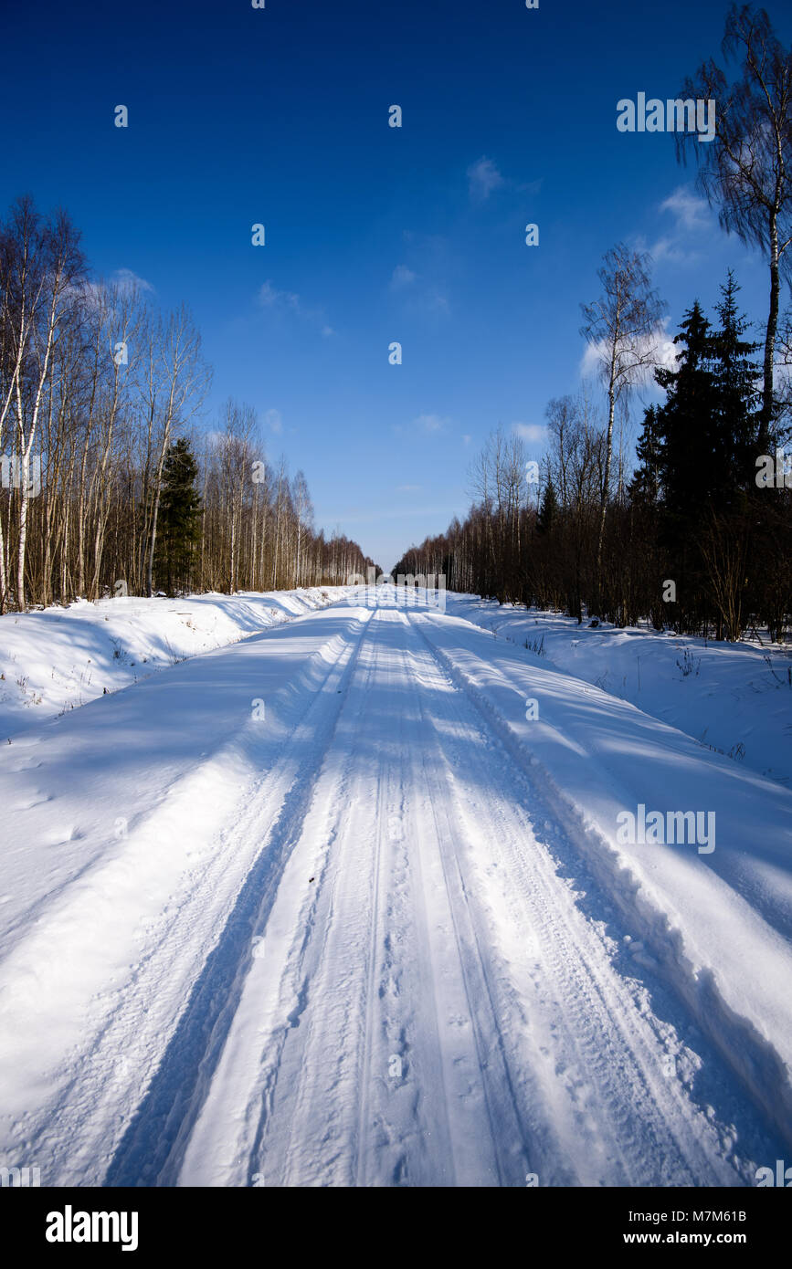 snowy winter road covered in deep snow with car tire tracks going in ...