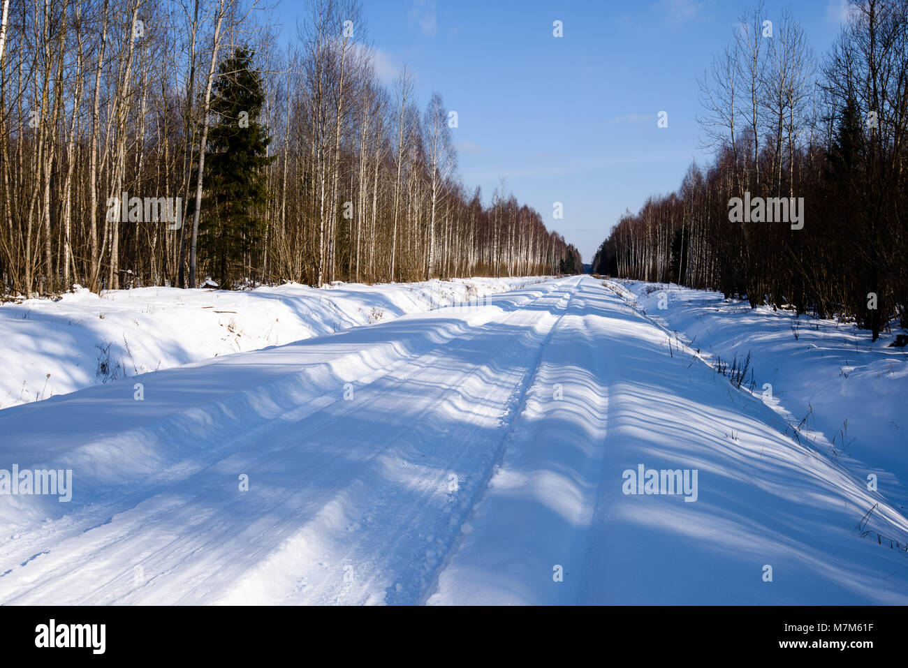 snowy winter road covered in deep snow with car tire tracks going in ...