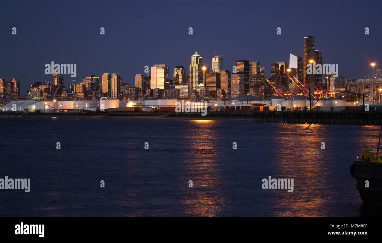 Gold light shimmers in the water reflecting illuminated buildings in ...