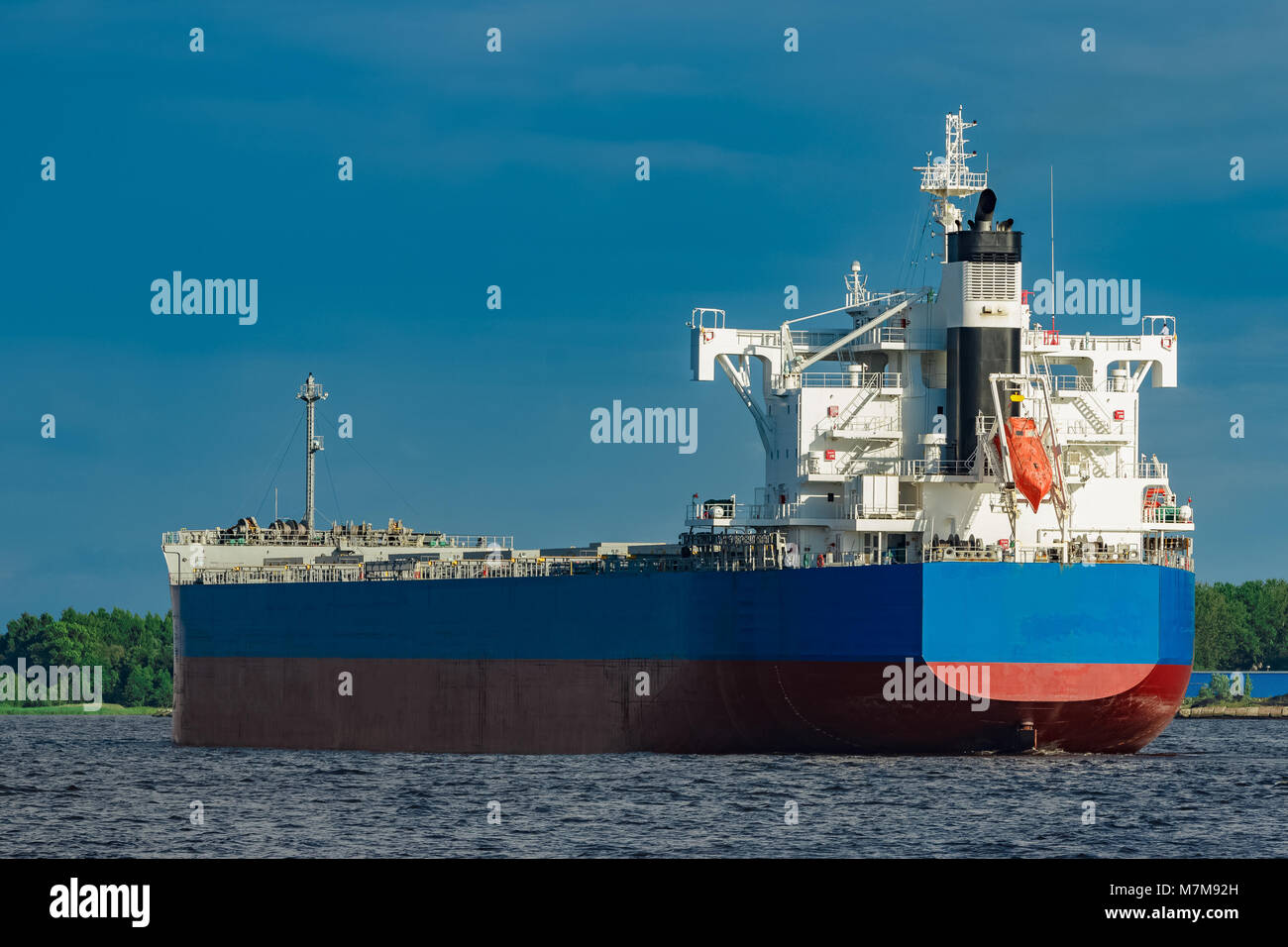 Merchandise import. Large blue cargo ship moving to Riga port Stock ...
