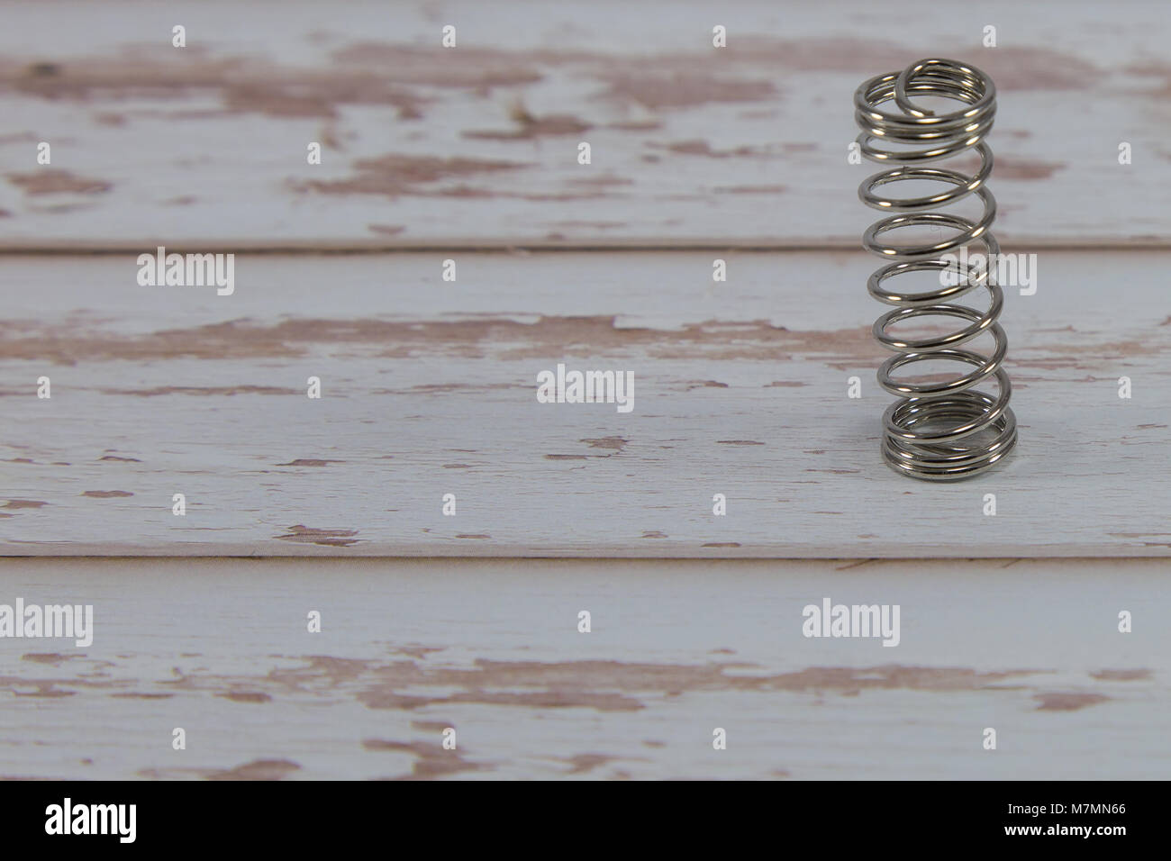 Little Spiral Metallic Spring on White Wooden Table Stock Photo - Alamy
