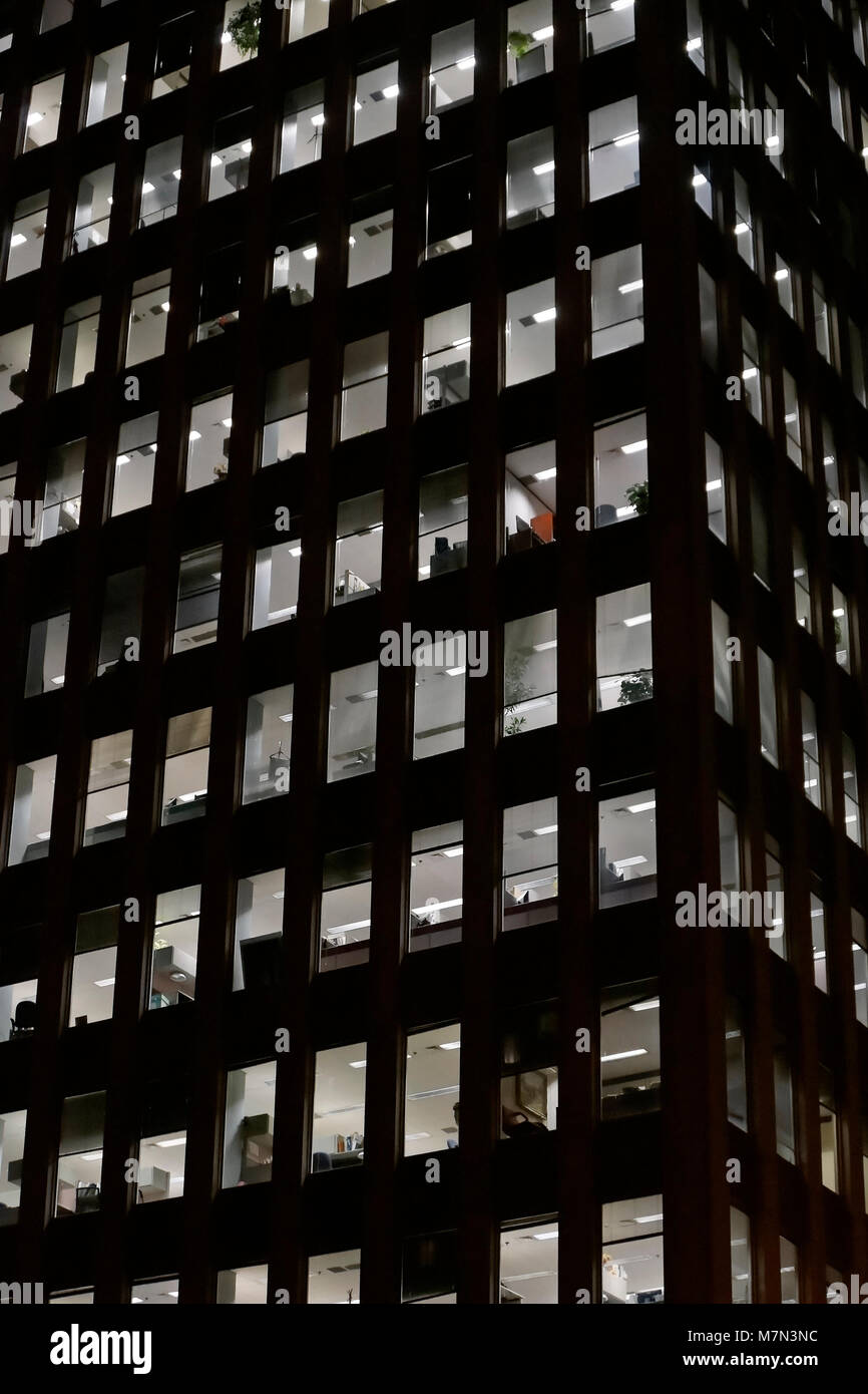 Empty offices in a high-rise office building at night with lights on ...