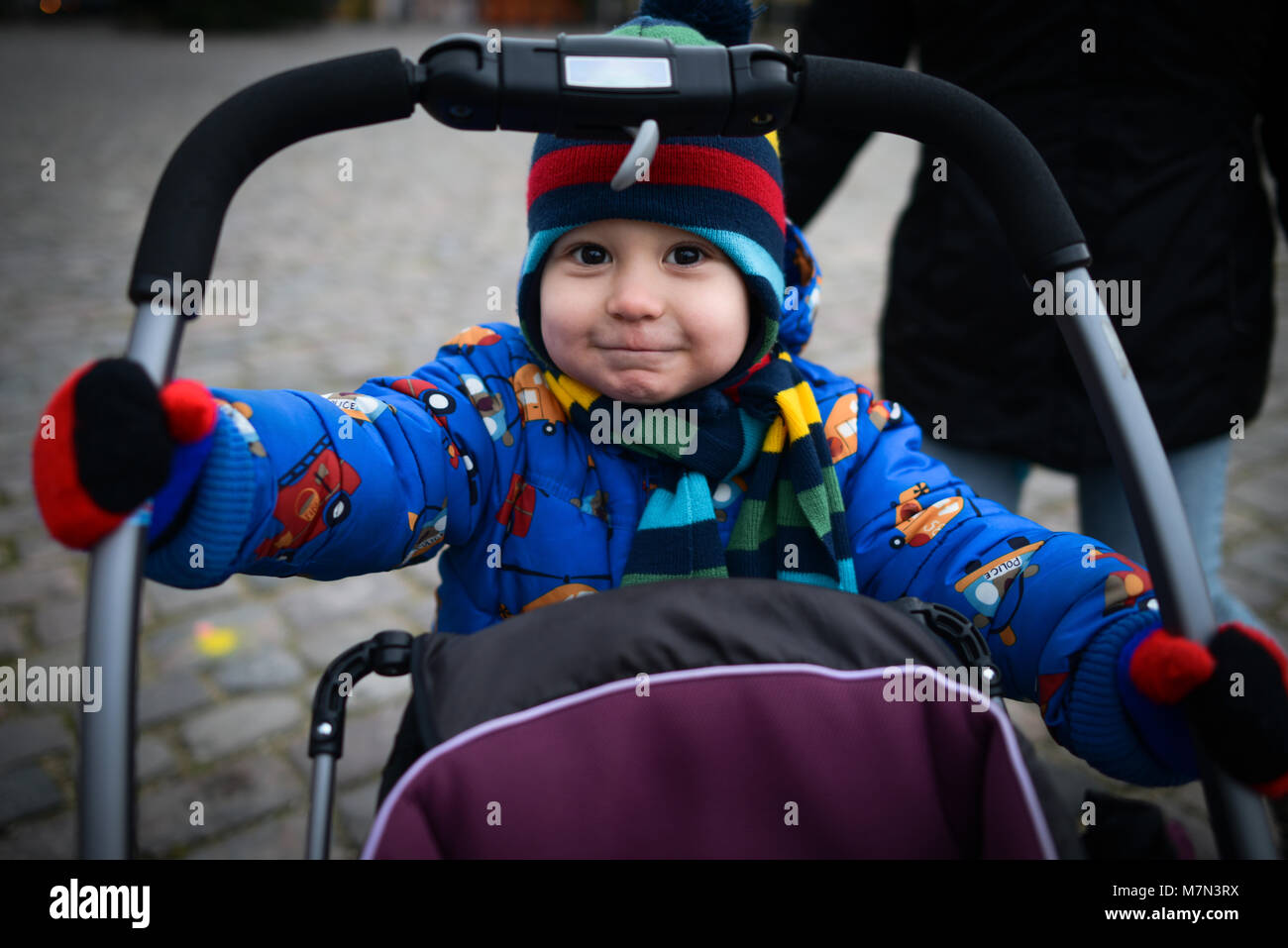 Cute little boy rolls baby stroller on the street. Beautiful child ...