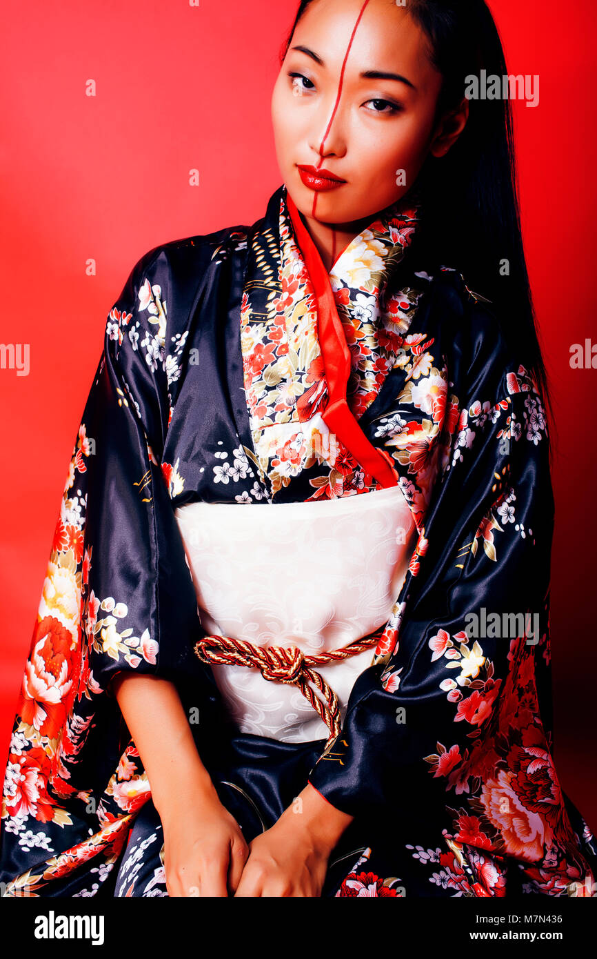 young pretty geisha on red background posing in kimono, oriental people ...