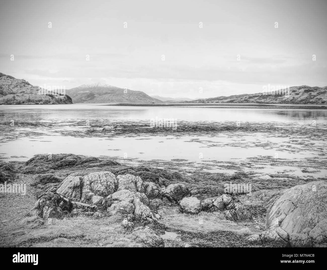 Rocks and boulders on shore. Poor warm sunset light, smooth water. Skye ...