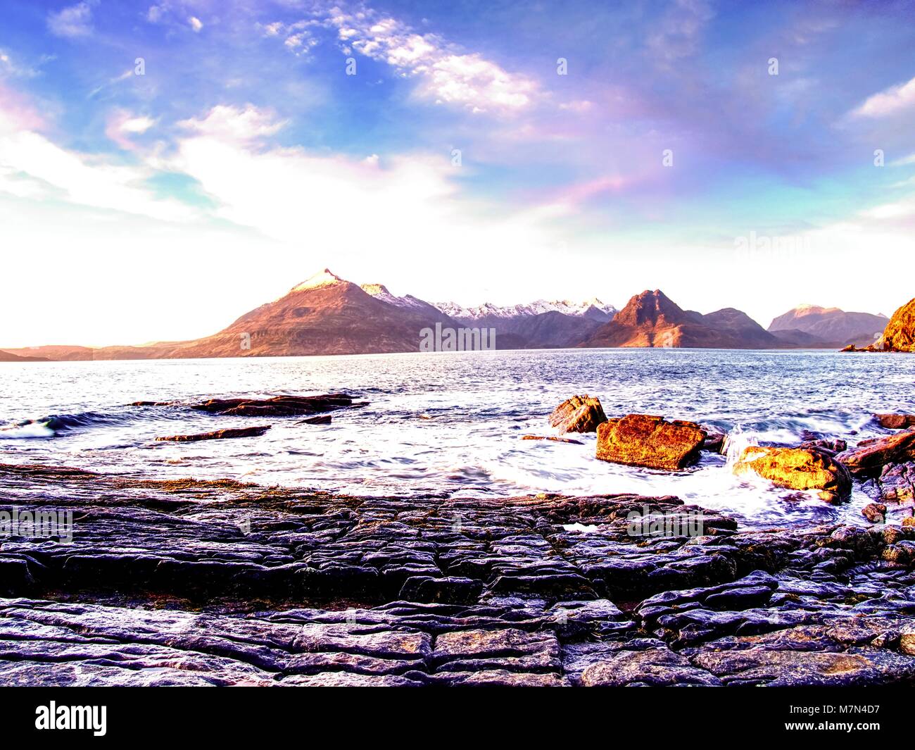 Evening rocky shore with sea water and large cracked rocks with erosion ...