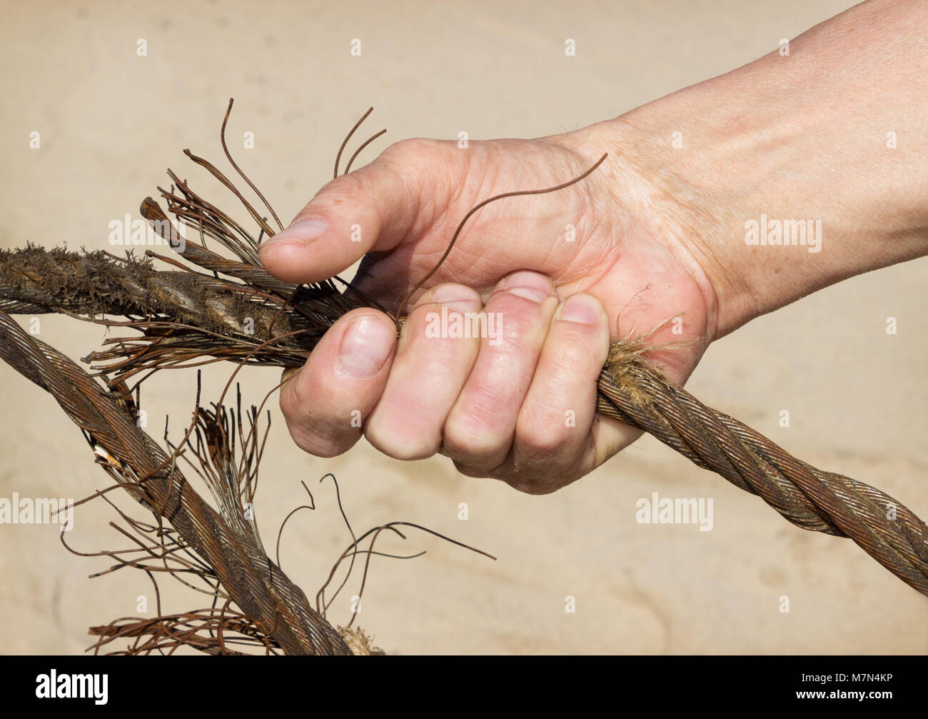 Human hand compresses old steel cable on a background of sand Stock ...