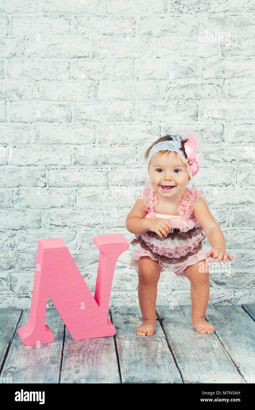 Beautiful and cute girl in pink dress with the letter N. Emotional girl ...