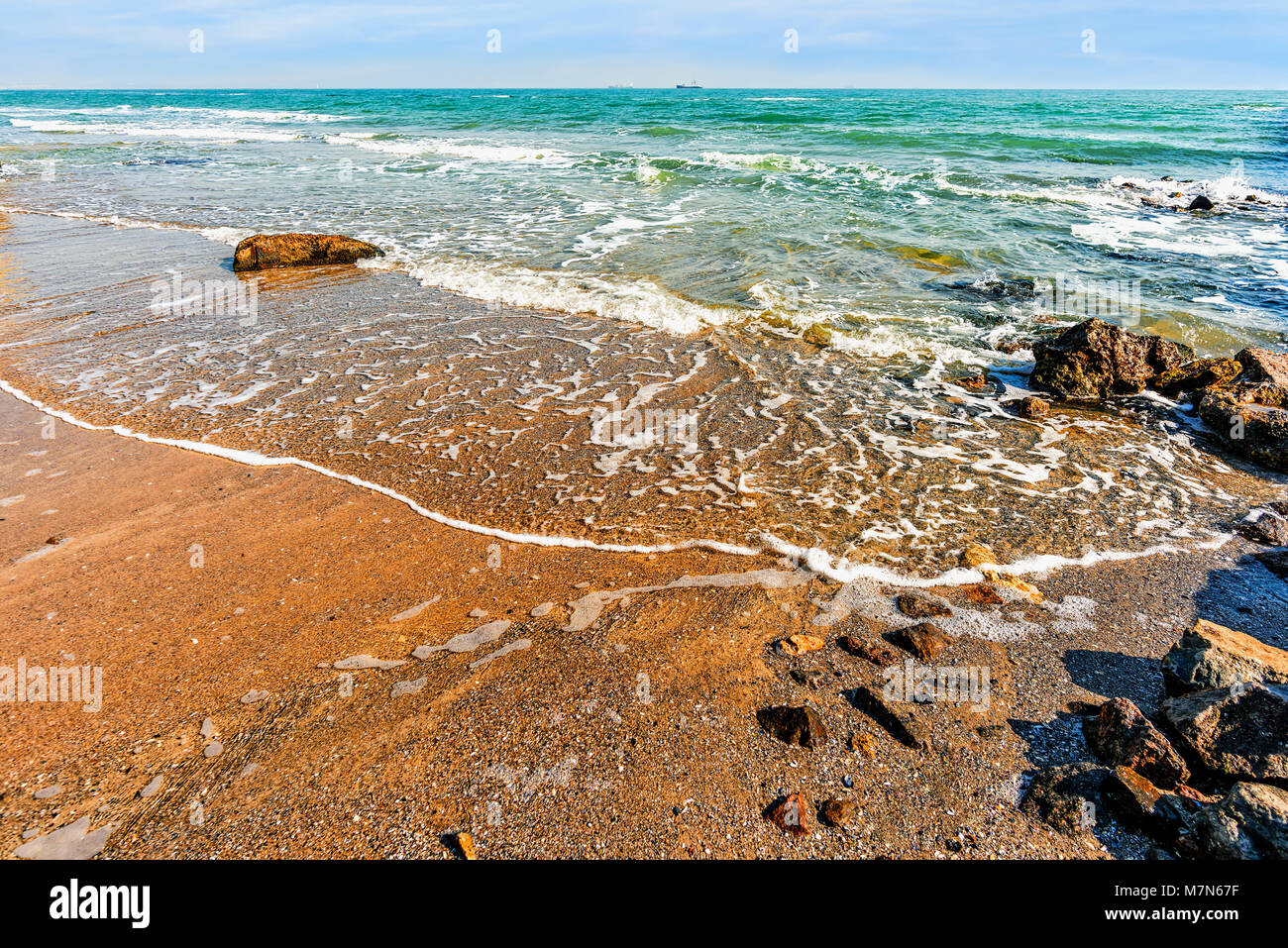 sandy beach of the ocean with rocks and rocks, sea waves with white ...