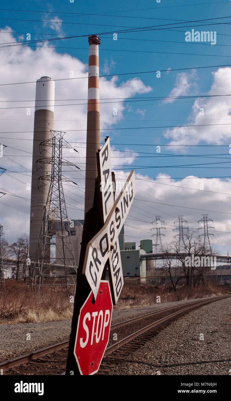 A railroad crossing and stop sign next to train tracks in an industrial ...