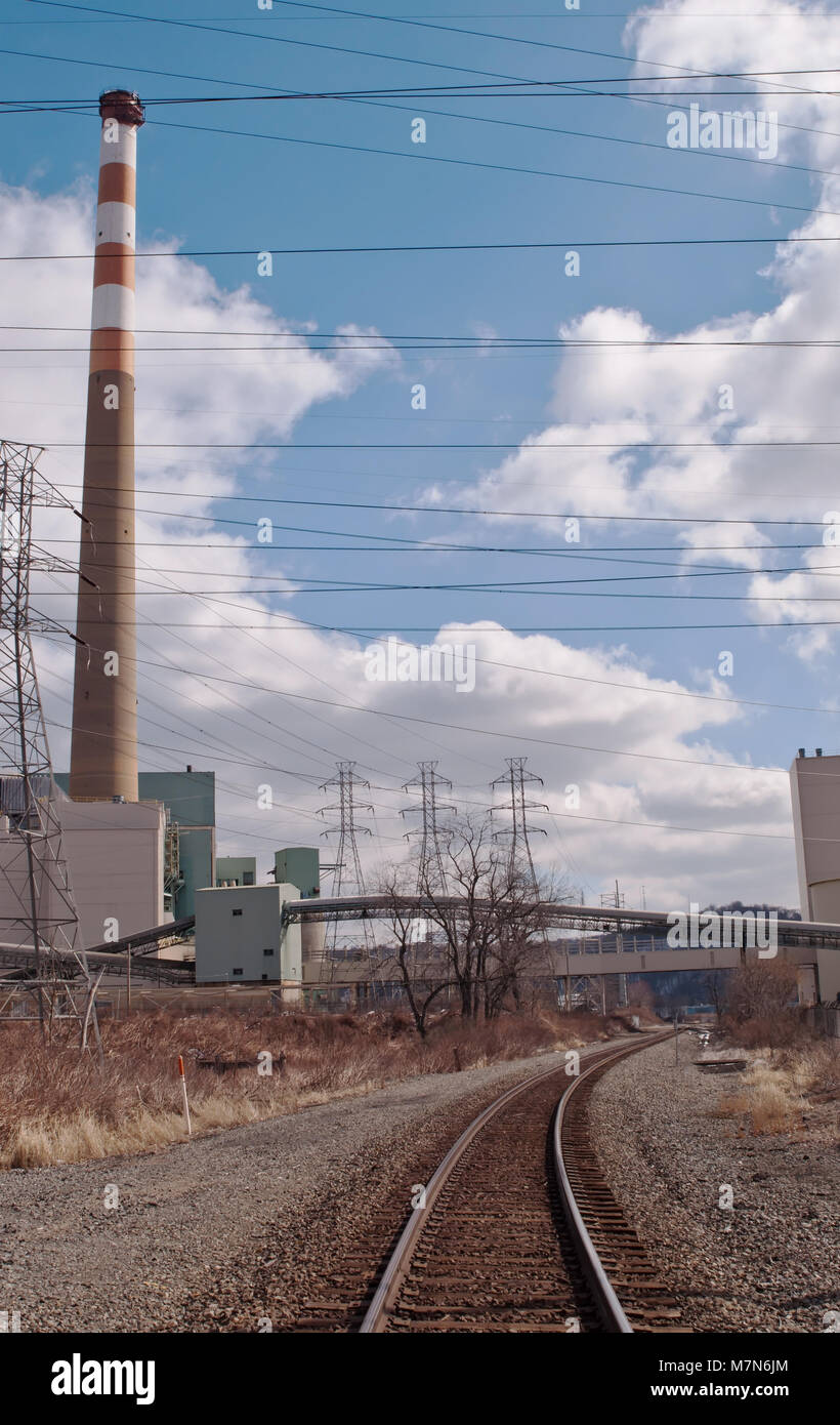 Train tracks running through a power station under a pretty blue sky ...