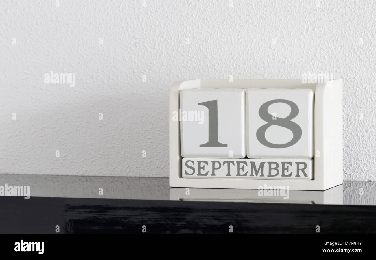 White block calendar present date 18 and month September on white wall ...