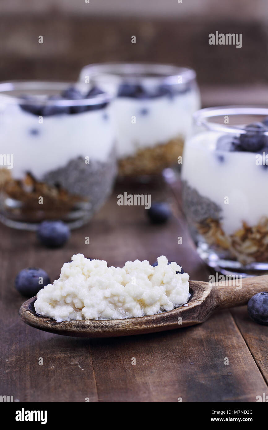 Kefir grains in wooden spoon in front of cups of Kefir Yogurt Parfaits ...
