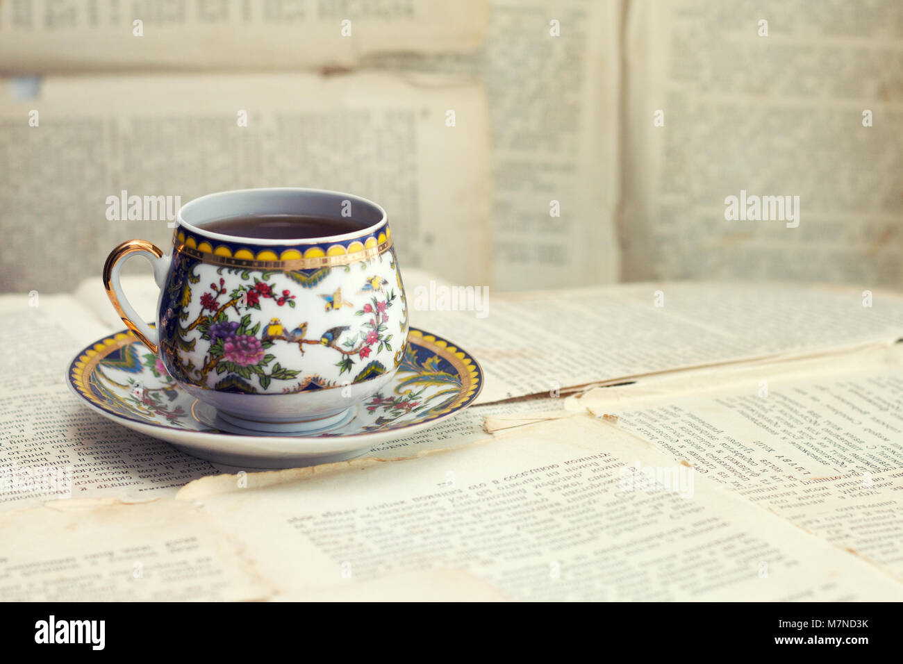 An old cup of coffee on the background of old sheets from the book ...