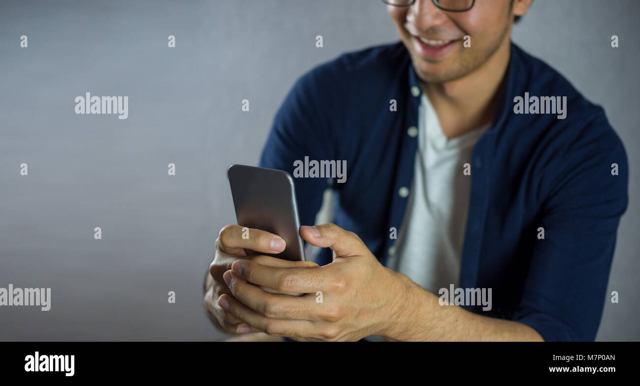 Men smiling using phone on grey background Stock Photo - Alamy
