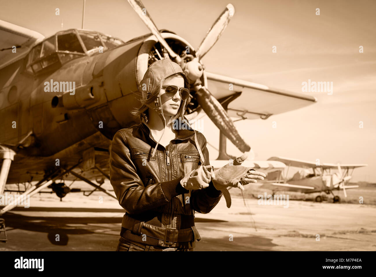Portrait of beautiful female pilot with plane behind. Sepia photo Stock ...