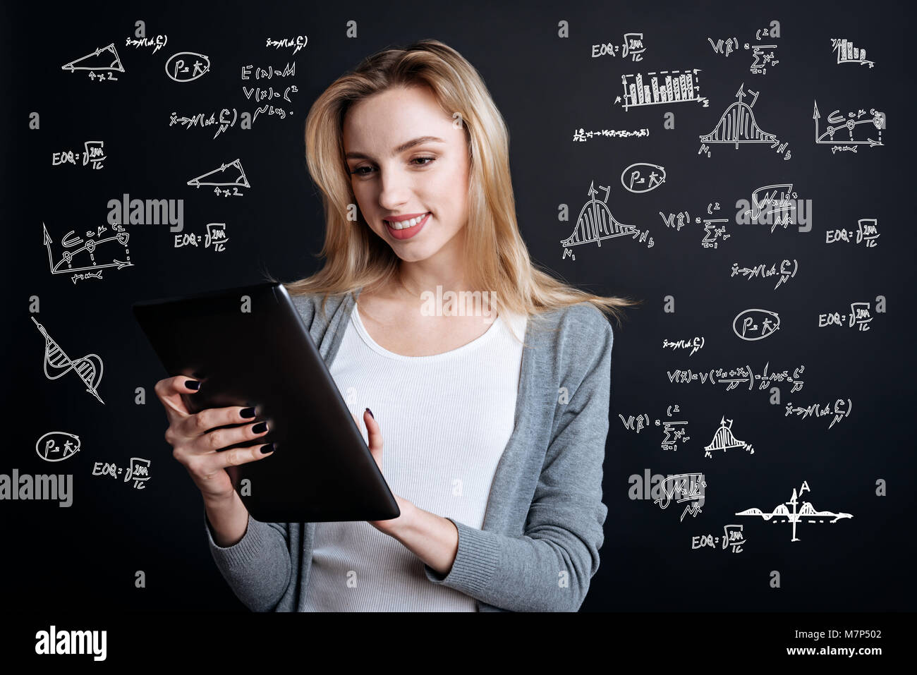 Calm person smiling while holding a useful tablet and working Stock ...